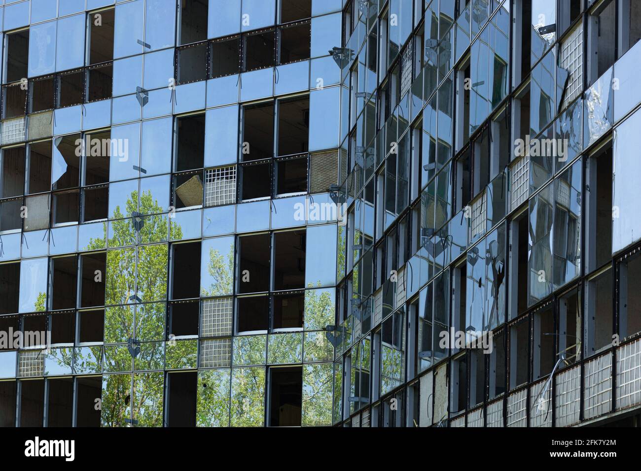 Abandoned modern glass building with broken windows and reflection of ...