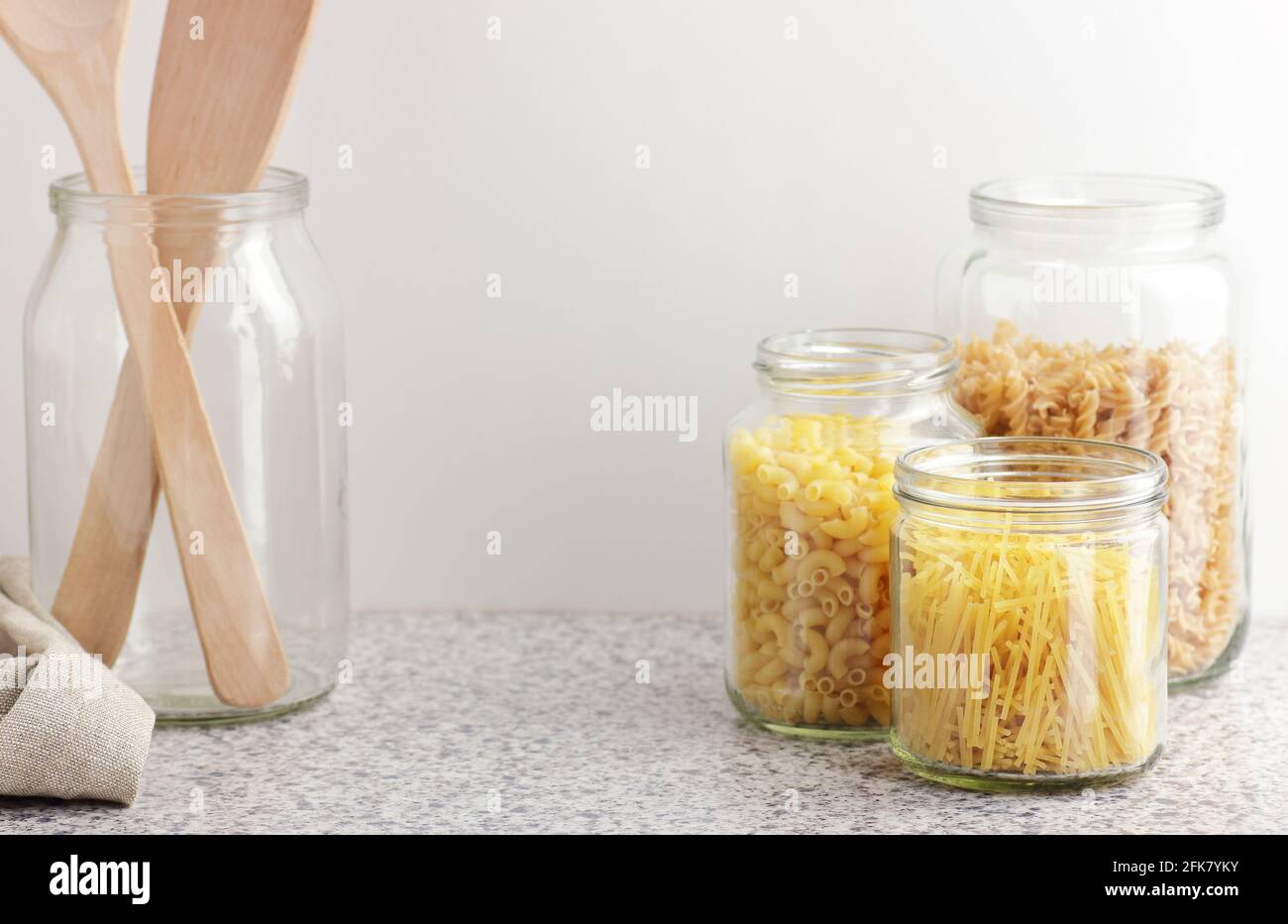 Variety of italian pasta in glass jars uncooked on white kitchen ...