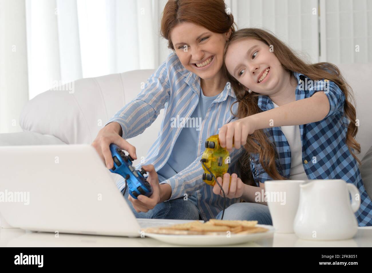 Smiling mother and daughter using laptop playing video game Stock Photo ...