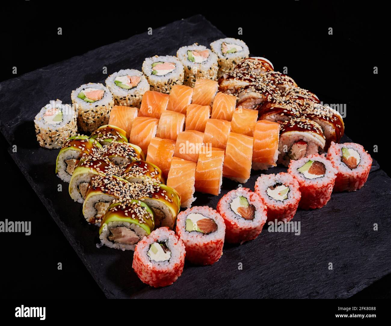 Large square stone board with sushi set of different types of rolls ...