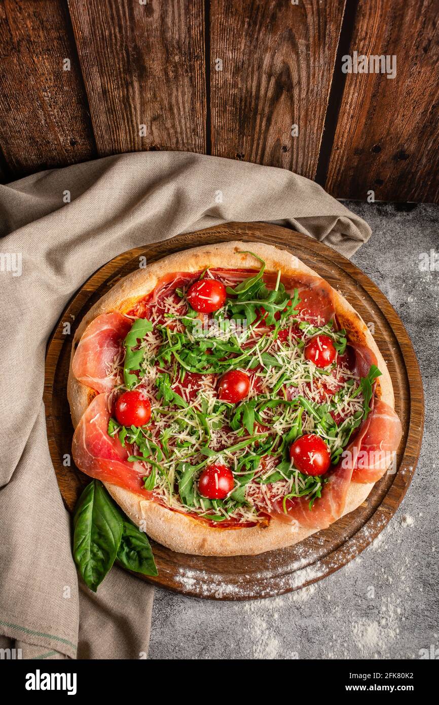 Italian pizza with a crispy crust on a round wooden tray. Pizza with ...