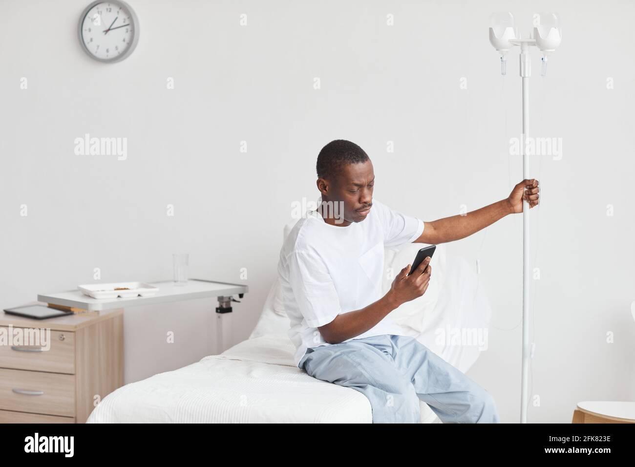 Portrait of young African-American man using smartphone in hospital ...