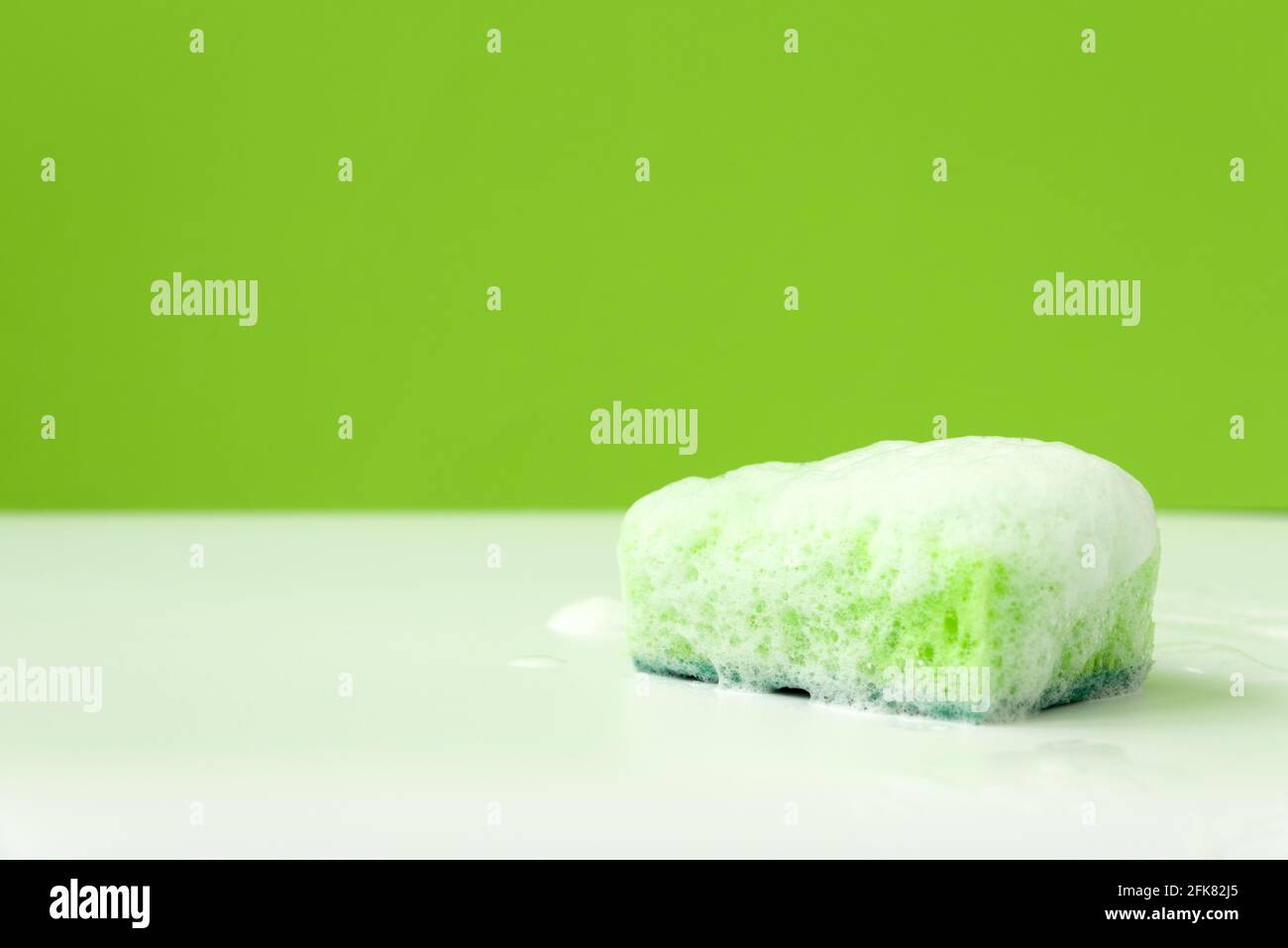 Green kitchen cleaning sponge with soap bubbles lying on white ...