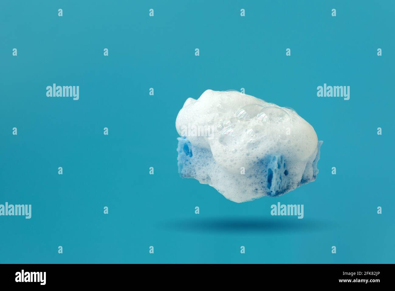 Blue kitchen cleaning sponge with soap bubbles on blue background ...