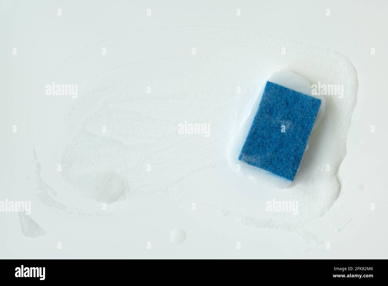Blue kitchen cleaning sponge with soap bubbles on white background. Top ...