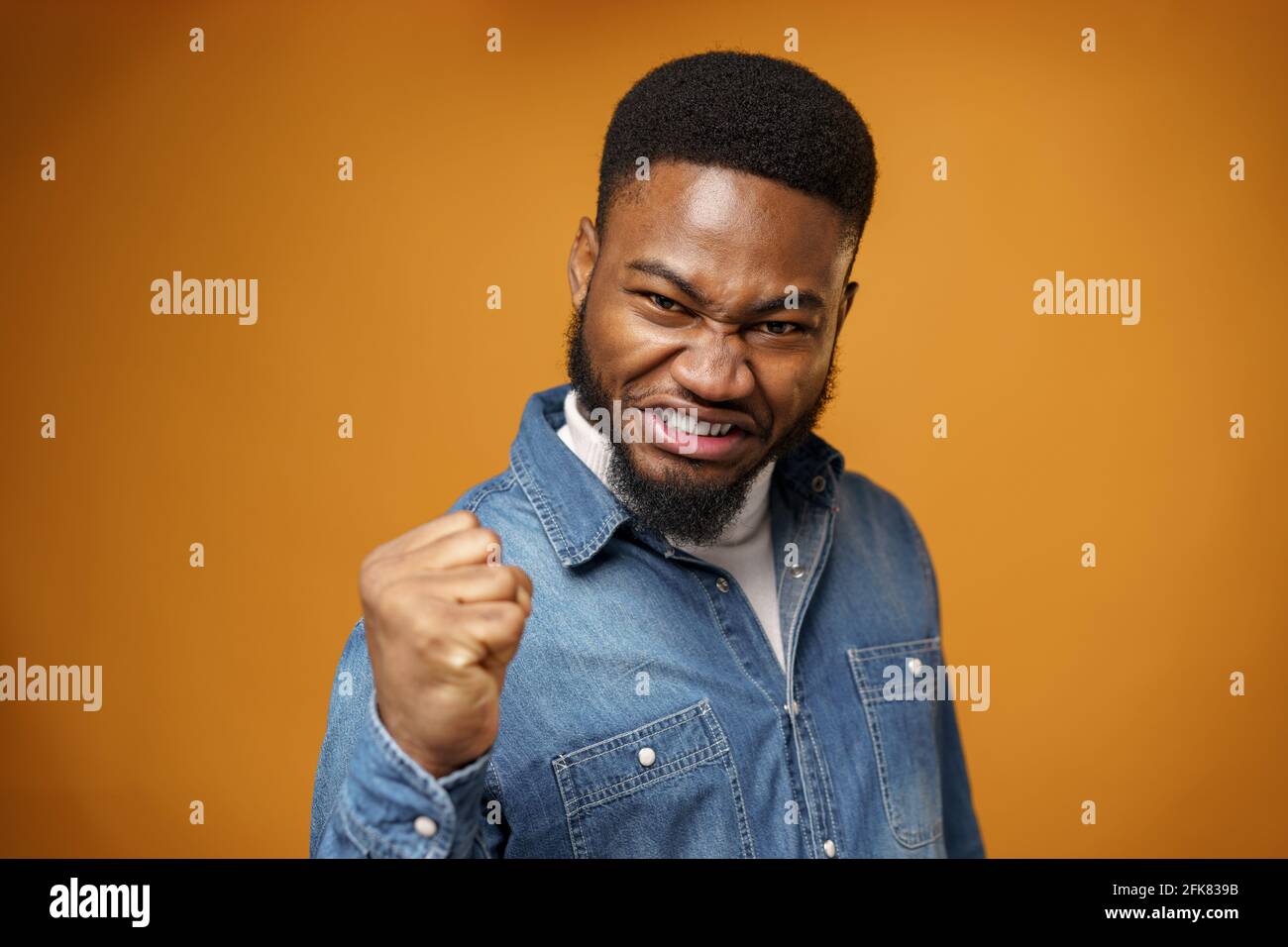Angry upset young man clenches fist against yellow background Stock ...
