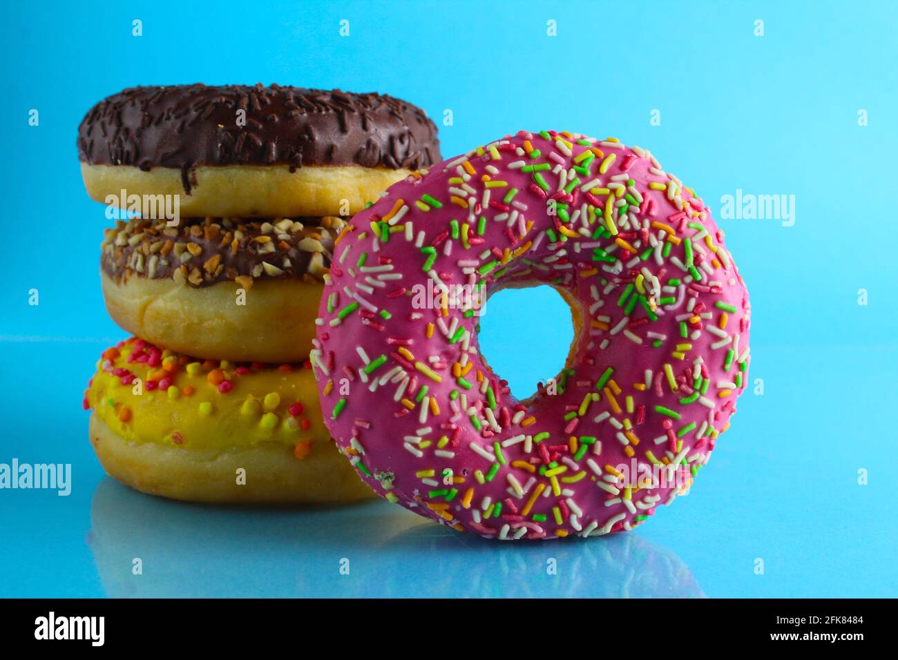 A still life food donut berliners in a pink glaze with a colored stands ...