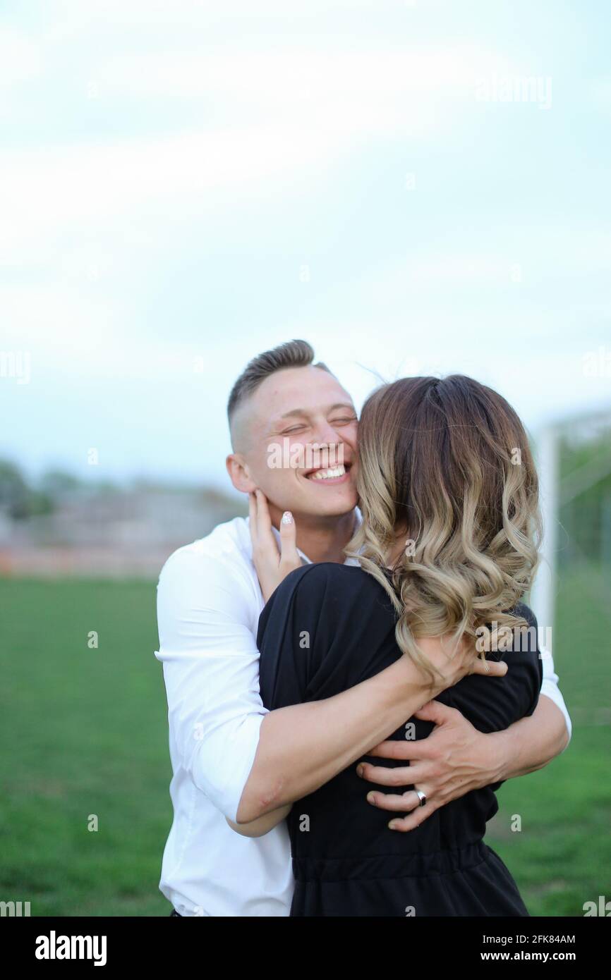 Portrait of young man hugging back view girl on football field Stock ...