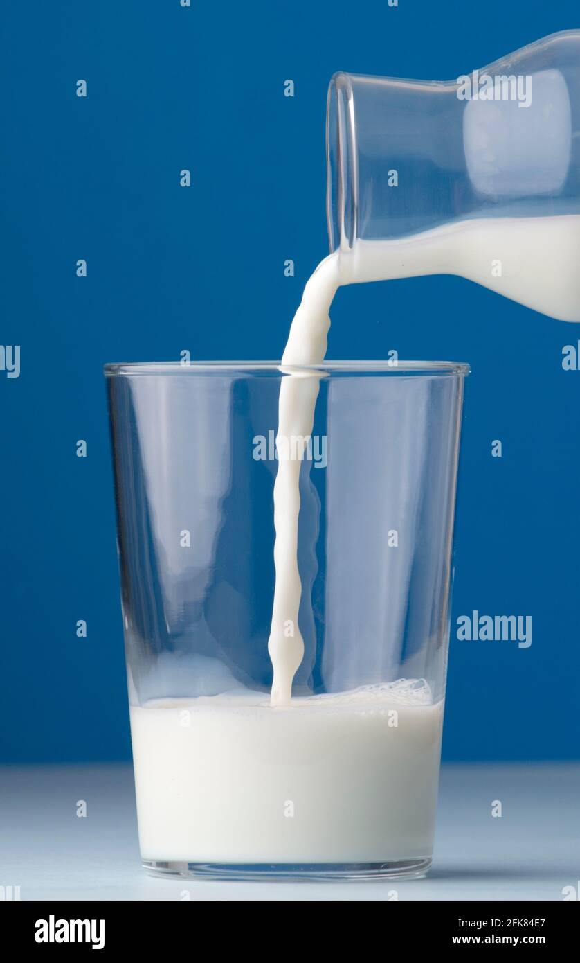glass of milk half full, with glass bottle, blue background Stock Photo ...