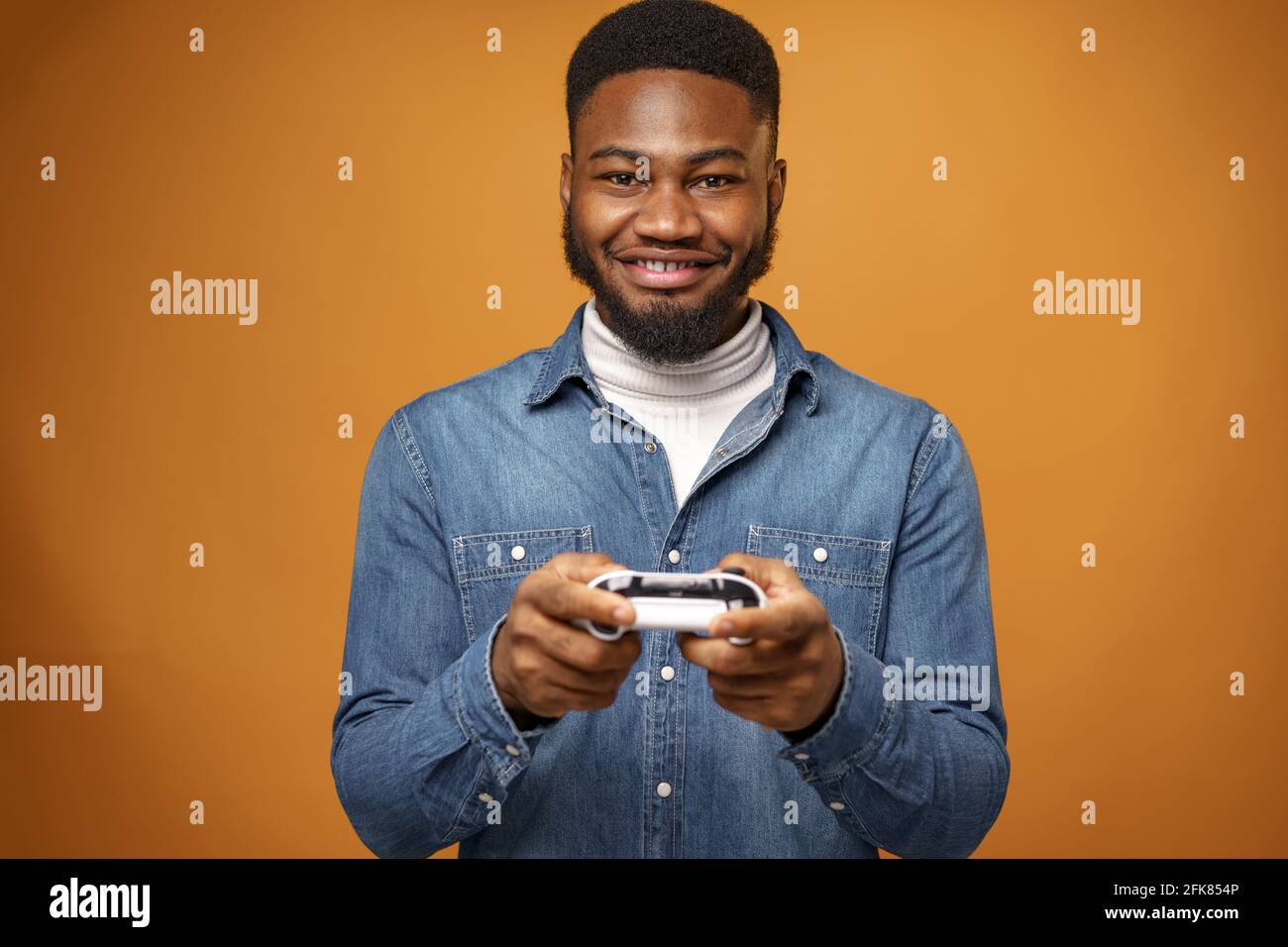 Young african american man holding joystick playing video games, yellow ...