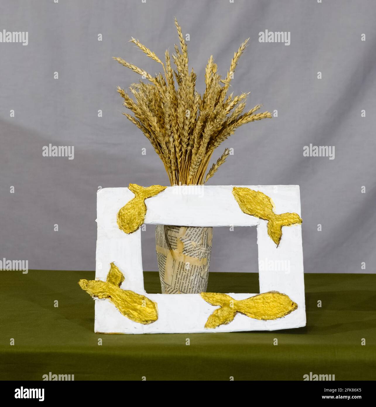 Cardboard vase from newspapers, in a vase of wheat. A photo frame with ...