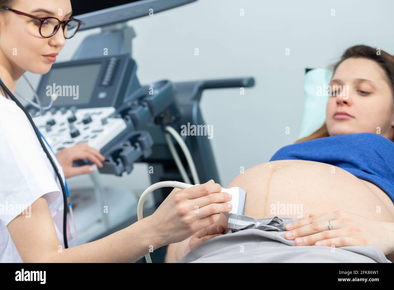 In the gynecology room, a lady doctor examines a pregnant woman using ...