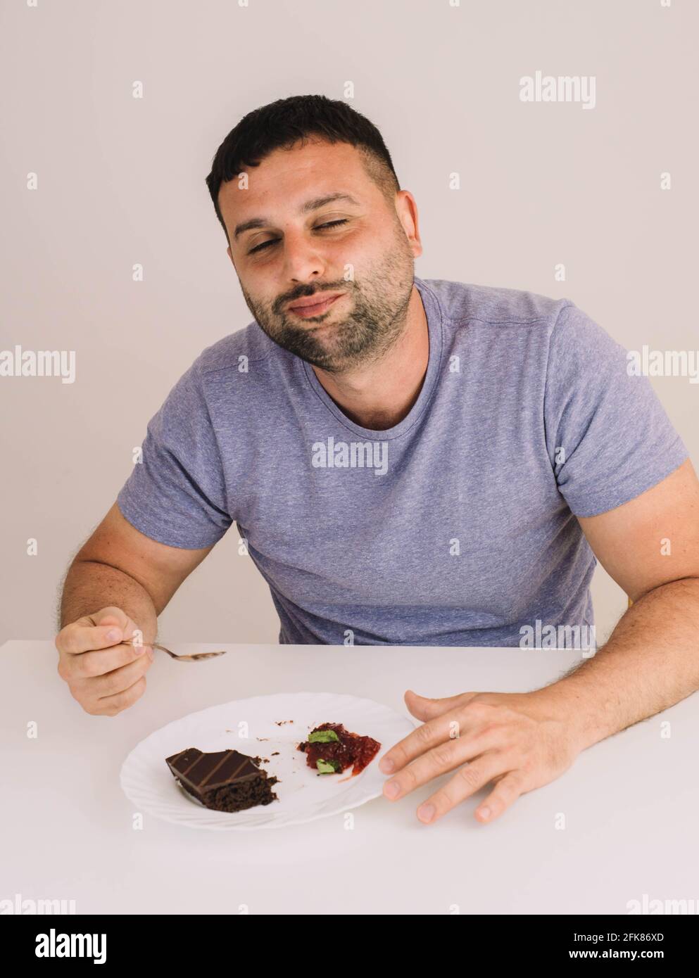 Man enjoying a chocolate cake with strawberry jam Stock Photo - Alamy