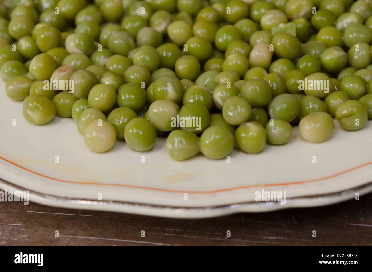 close-up of peas on plate and on wooden table, natural and fresh green ...