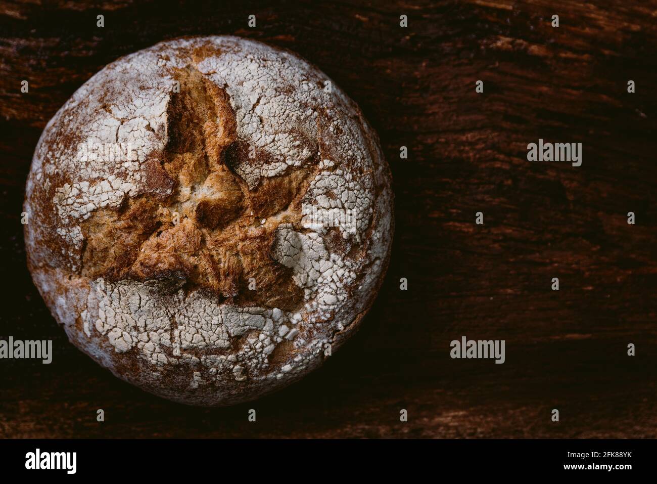 crusty round loaf of healthy whole grain bread on dark wooden table ...