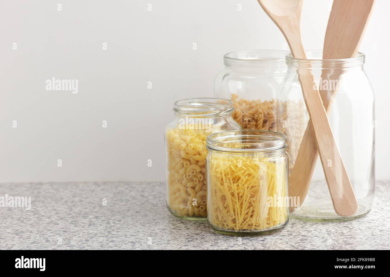 Variety of italian pasta in glass jars uncooked on white kitchen ...
