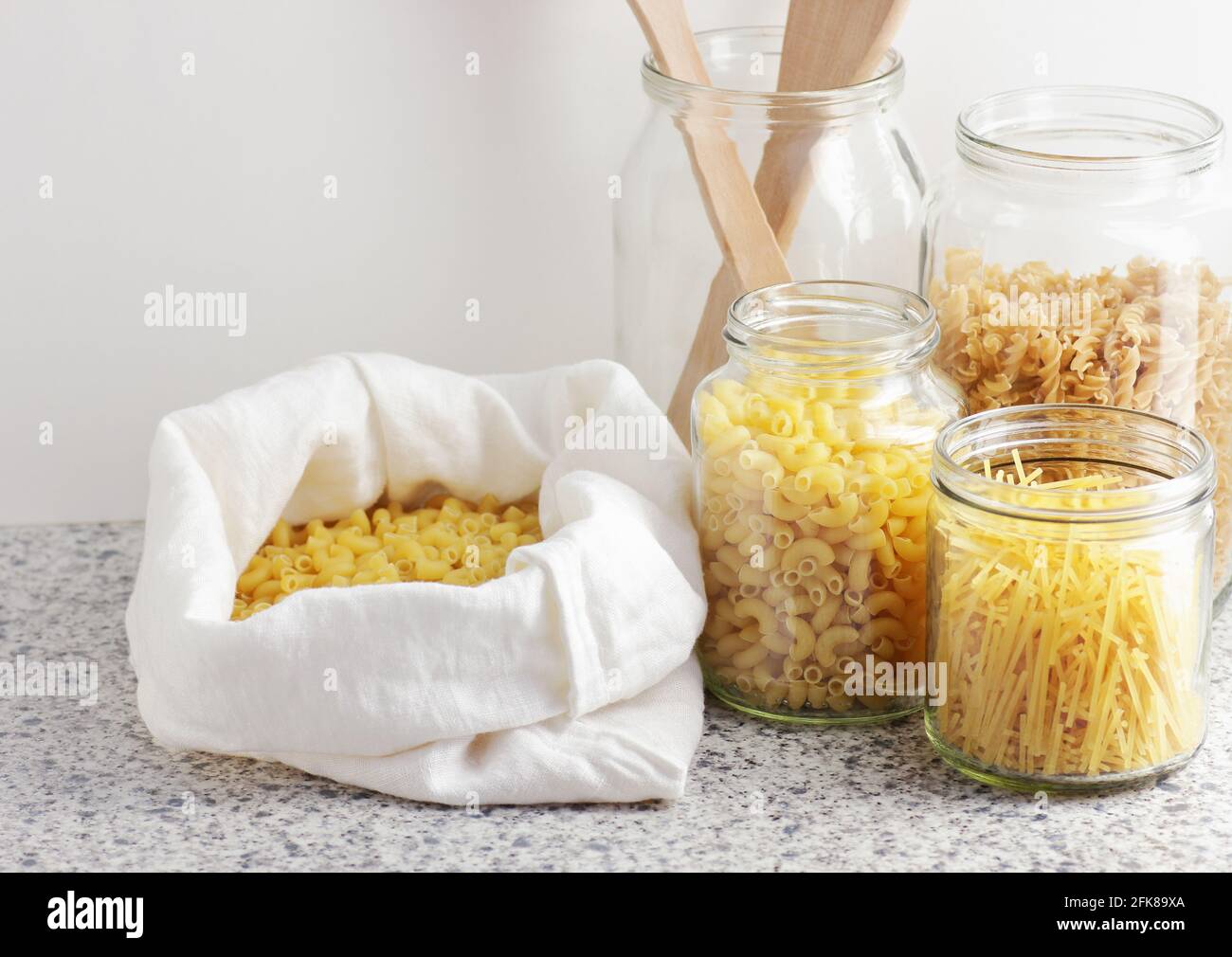 Variety of italian pasta in glass jars uncooked on white kitchen ...