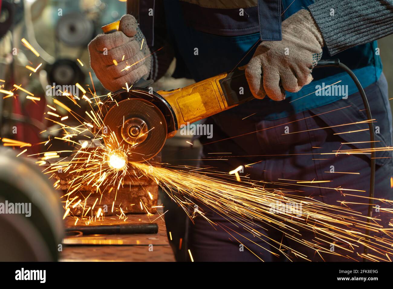 Locksmith in special clothes and goggles works in production. Metal ...