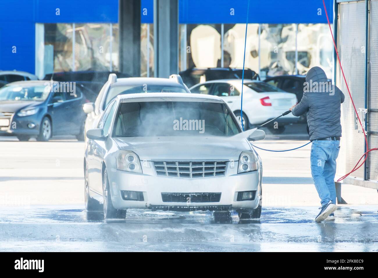 Man washing his car with using a high compression pressure water jet ...