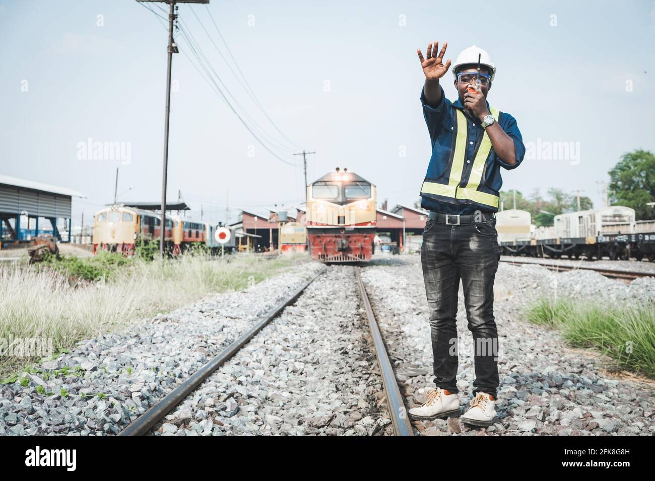 African engineer control a the train on railway with talking by radio ...