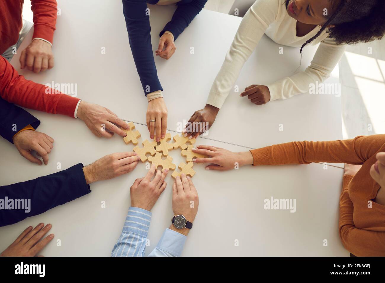 Multiracial office workers assembling wooden puzzles on desk ...
