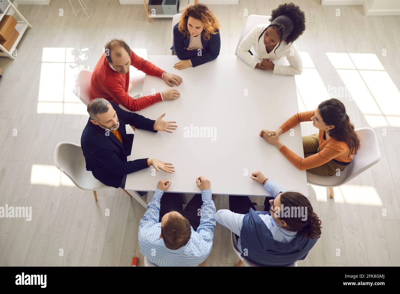 Group of company employees discussing work matters at office table in ...