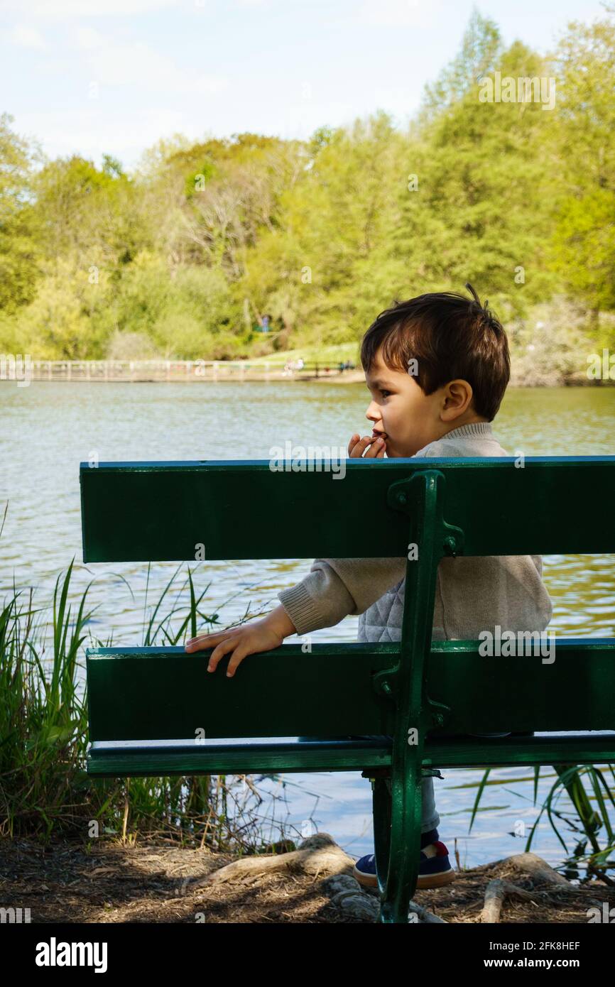 Little boy eating a biscuit on bench on lakeshore Stock Photo - Alamy