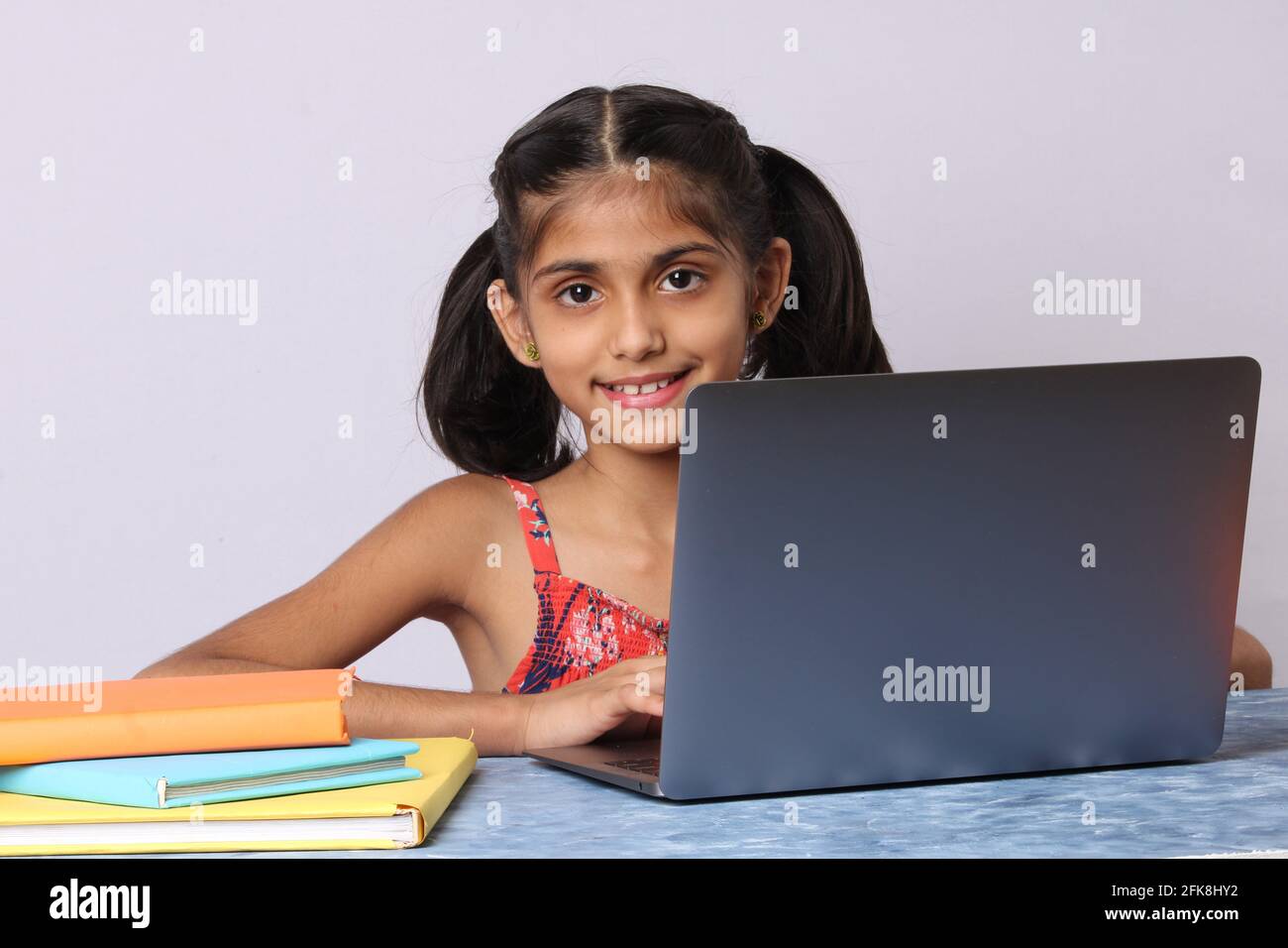 Little girl studying online using her laptop or computer at home Stock ...