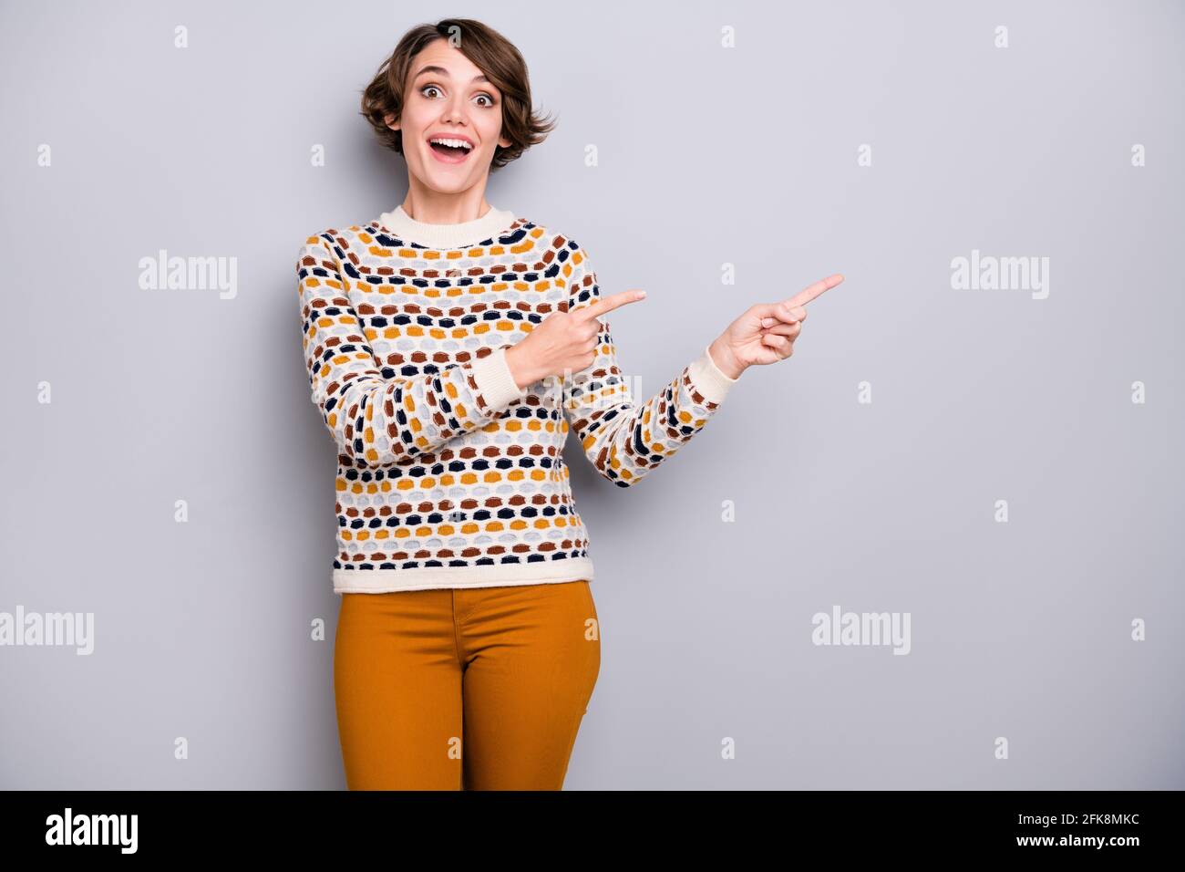 Portrait of pretty cheerful amazed brown-haired girl demonstrating ad ...