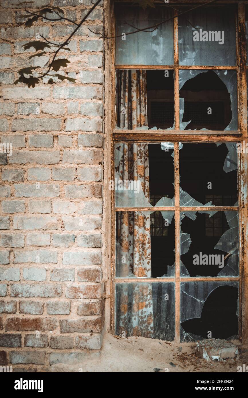 Eerie scenery of a shattered window of an old abandoned building with ...