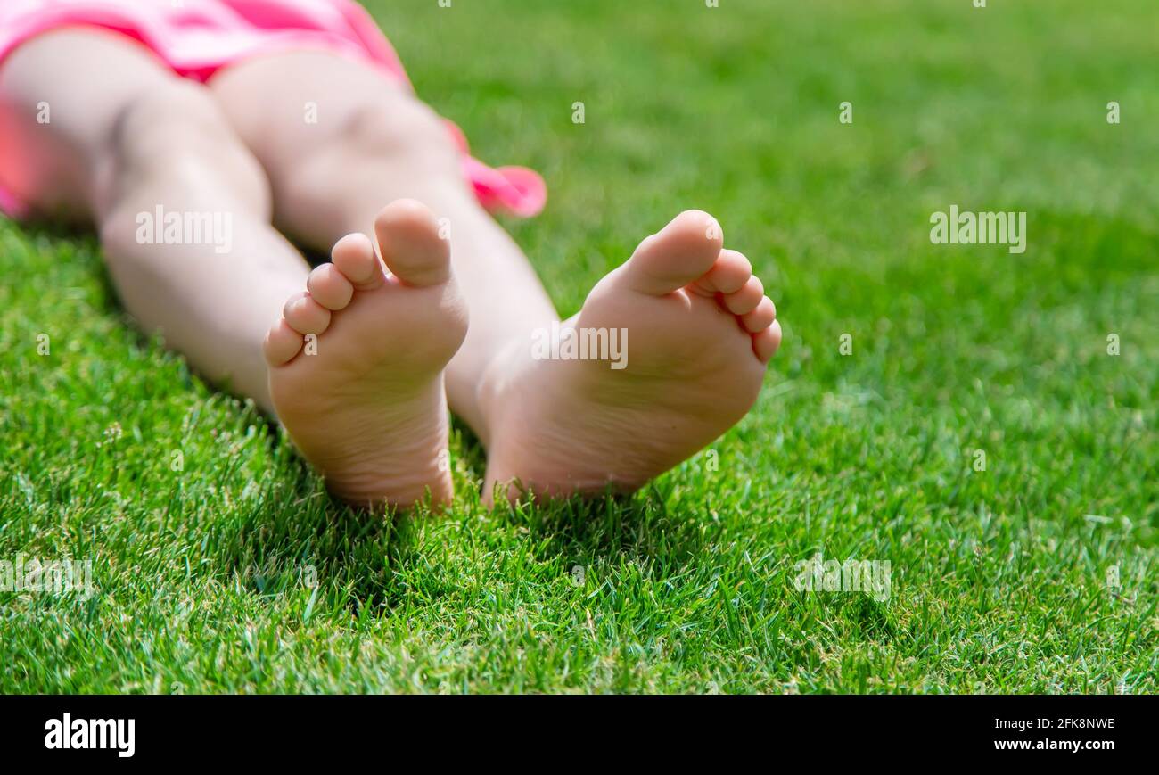 Feet of a child on the lawn on the grass. Selective focus. Kid Stock ...