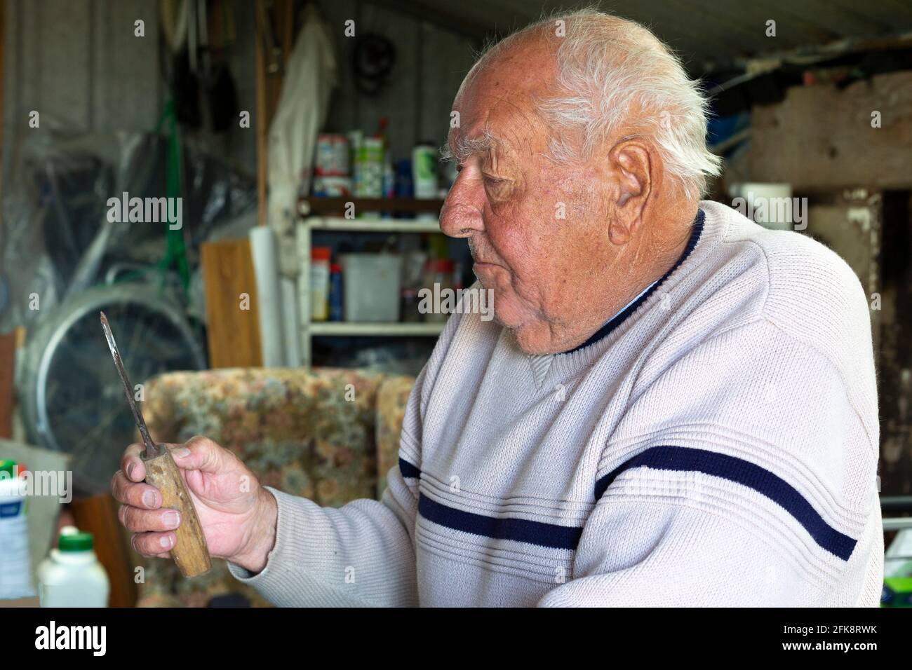 Elderly man in shed looking at old tool Stock Photo - Alamy