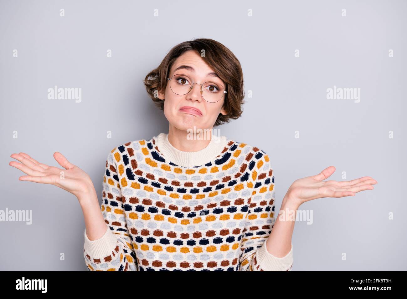 Portrait of attractive puzzled girl wearing specs shrugging shoulders ...