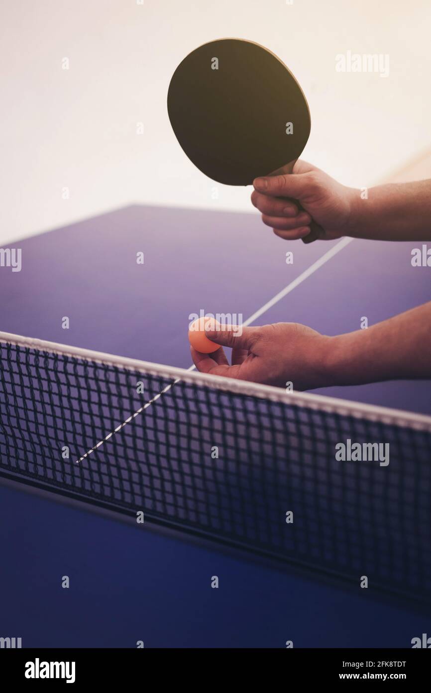 man is playing ping pong. He holds a ball and a racket in his hands ...