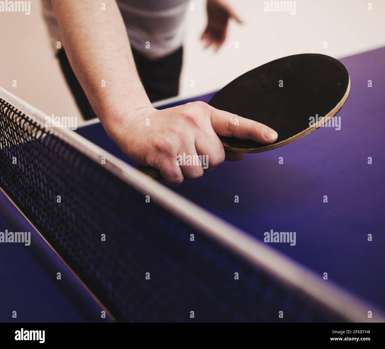 player's hand with a tennis racket on a blue table background. ping ...