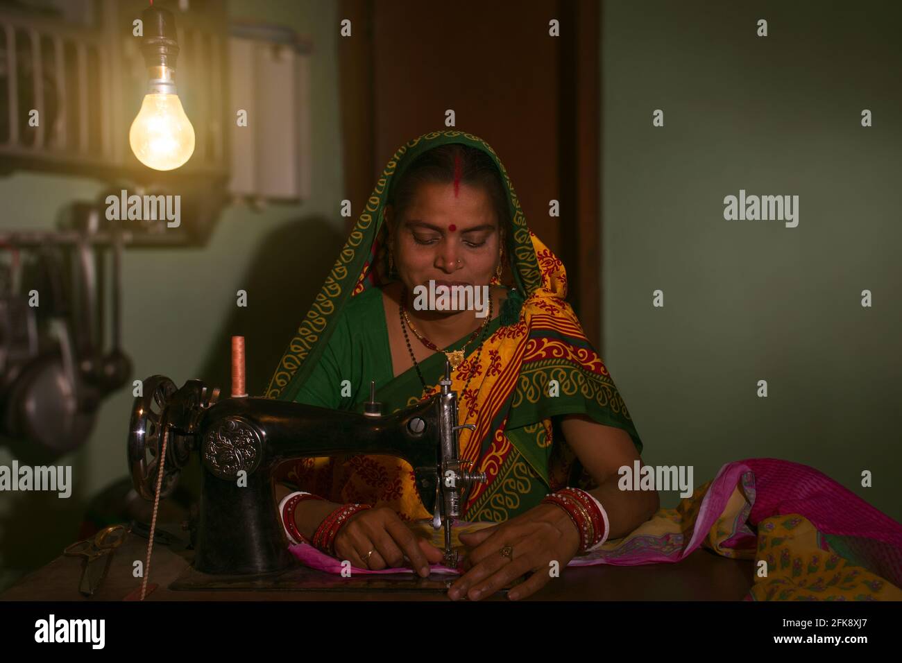 Indian Rural woman stitching clothes by sewing machine at home Stock ...