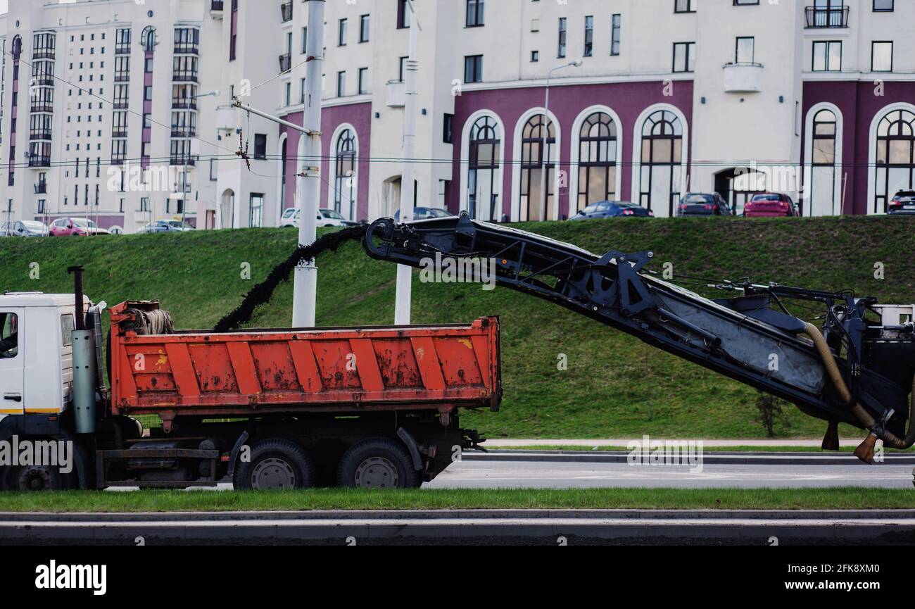 Road milling machine removes old asphalt and loads milled asphalt into ...