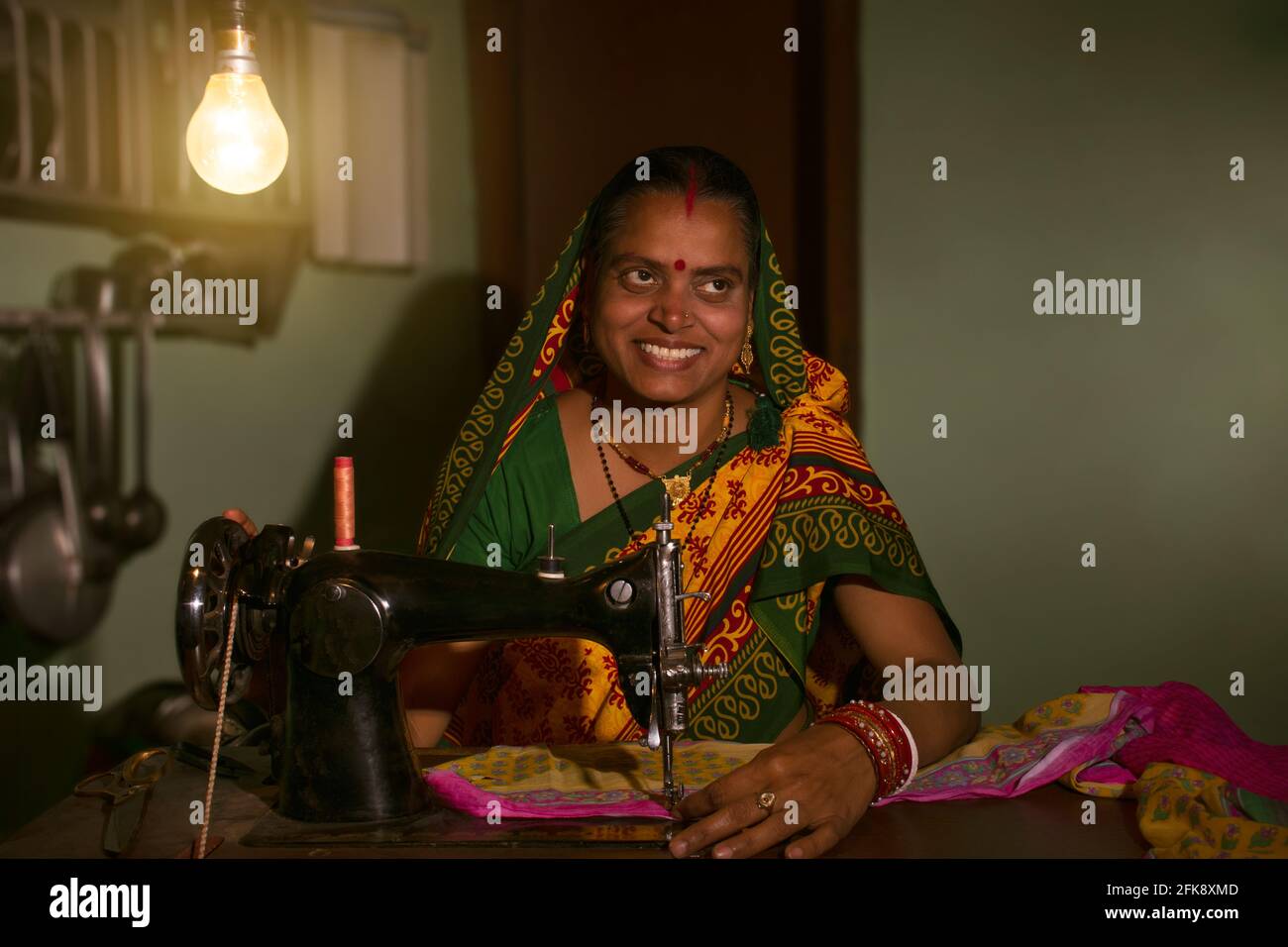 Indian Rural woman stitching clothes by sewing machine at home Stock ...