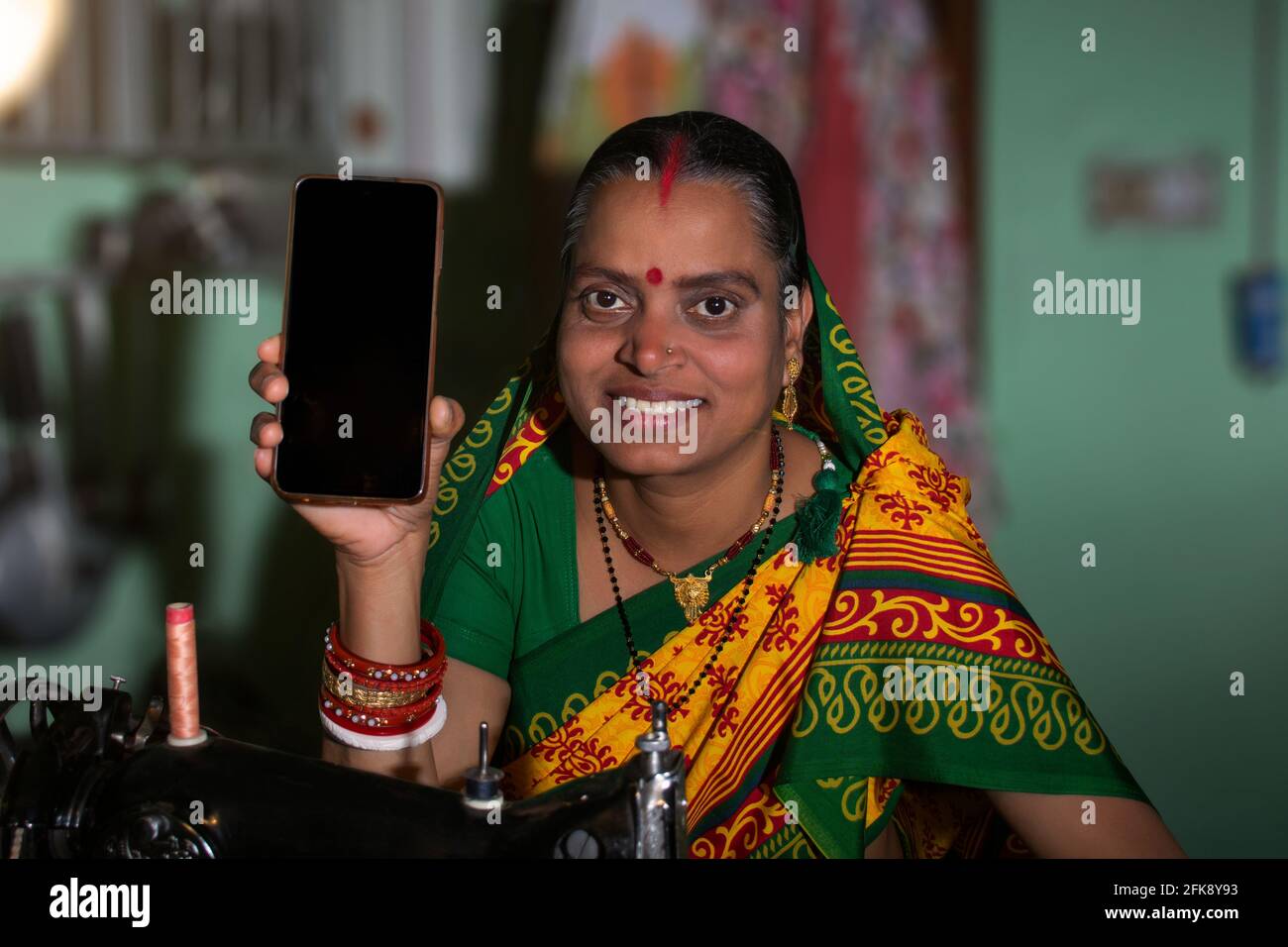 Indian rural woman using sewing machine and SHOWING HER MOBILE PHONE ...