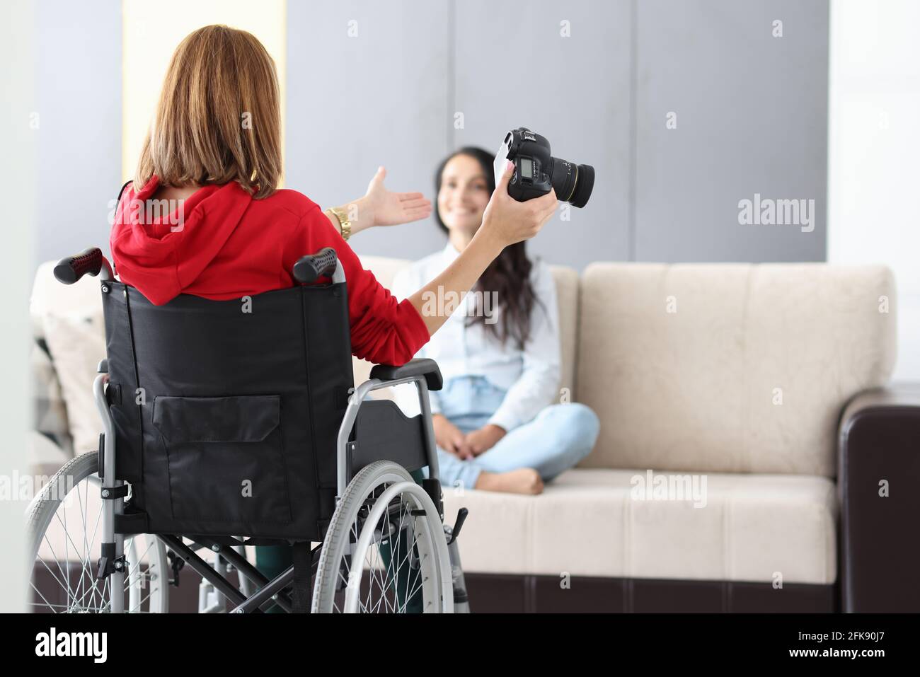 Woman in wheelchair holds camera and takes photo of model Stock Photo ...