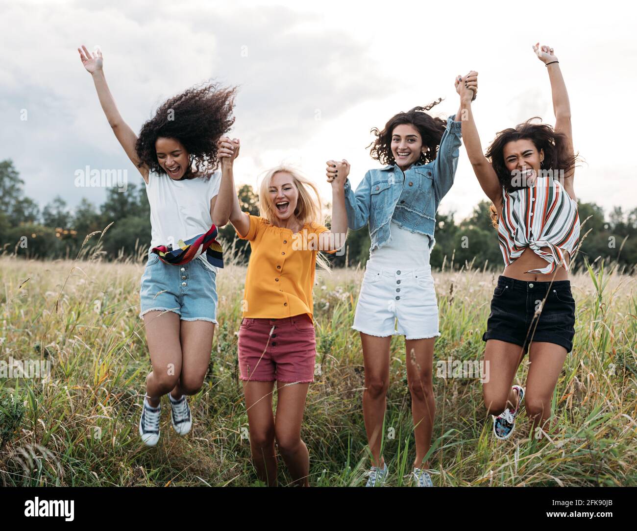 Group of diverse women jumping together outdoors. Friends having fun ...
