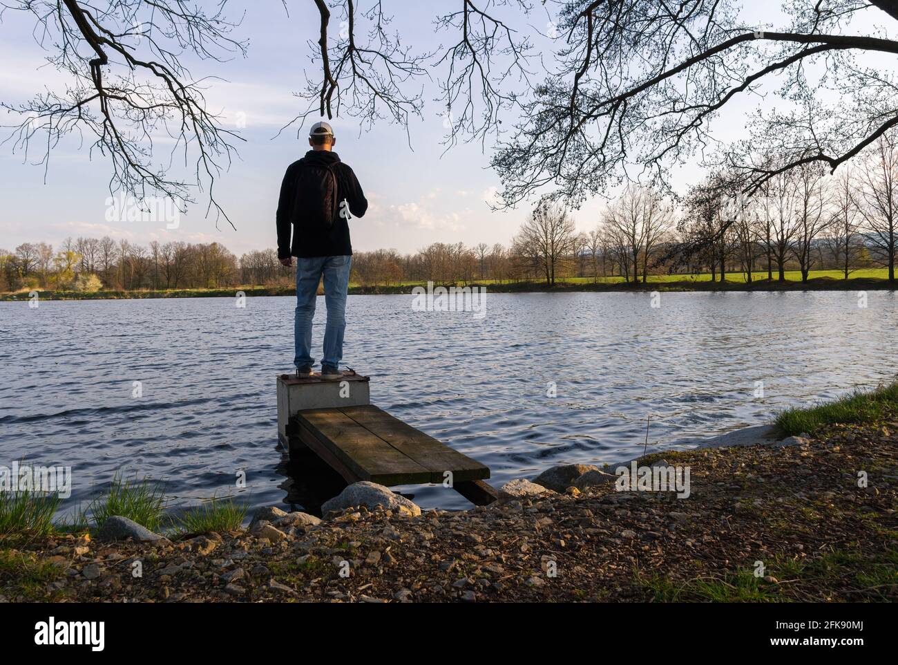 Young caucasian man with backpack stading on water gate pond. Czech ...