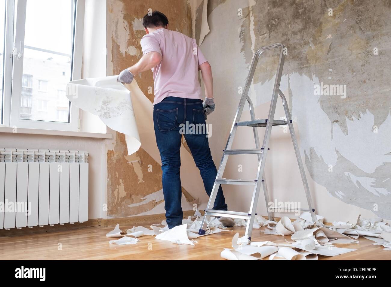 Process of flat renovation. Caucasian man tearing off old wallpaper ...