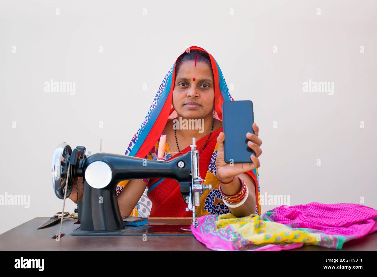 Indian rural woman using sewing machine and SHOWING HER MOBILE PHONE ...