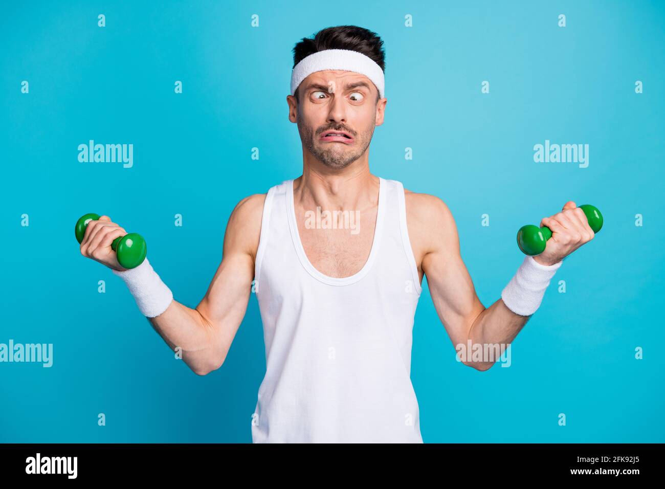 Photo of young sportsman train exercise with heavy dumbells grimacing ...