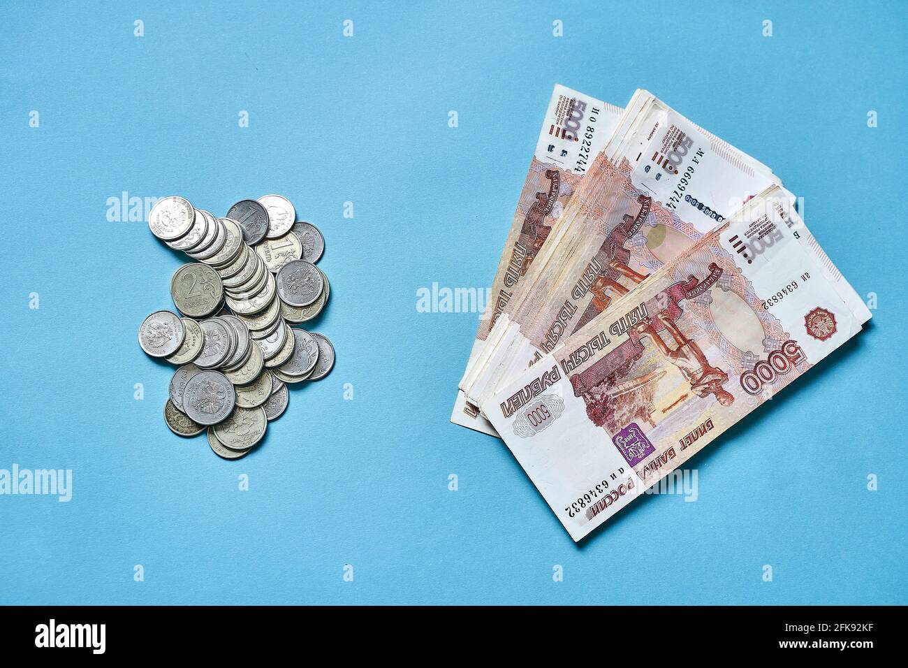 Many small Russian coins and five-thousand-dollar bills on a blue ...