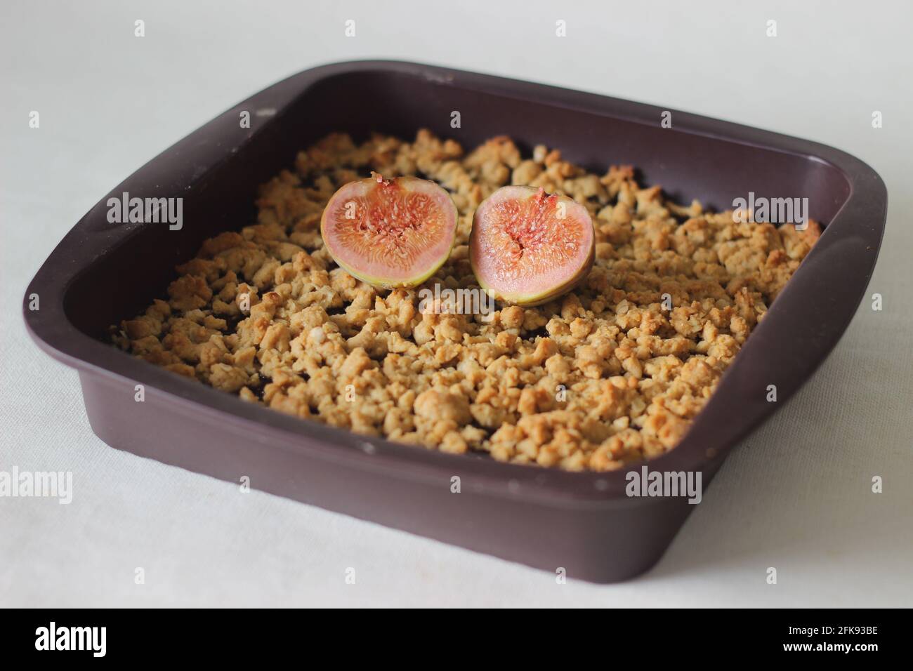 Home baked Fig crumble inside silicon bake dish. Shot on white ...