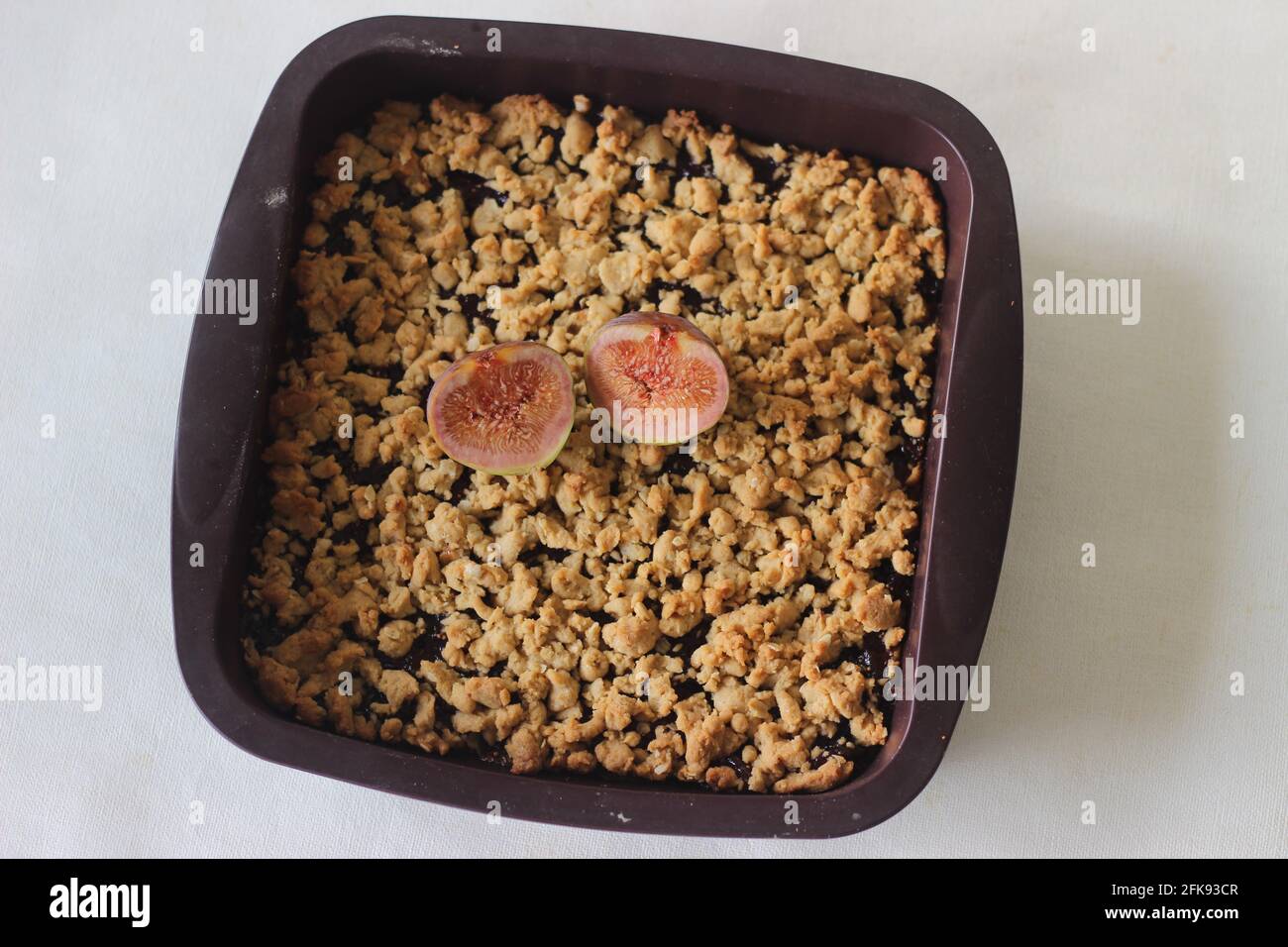 Home baked Fig crumble inside silicon bake dish. Shot on white ...