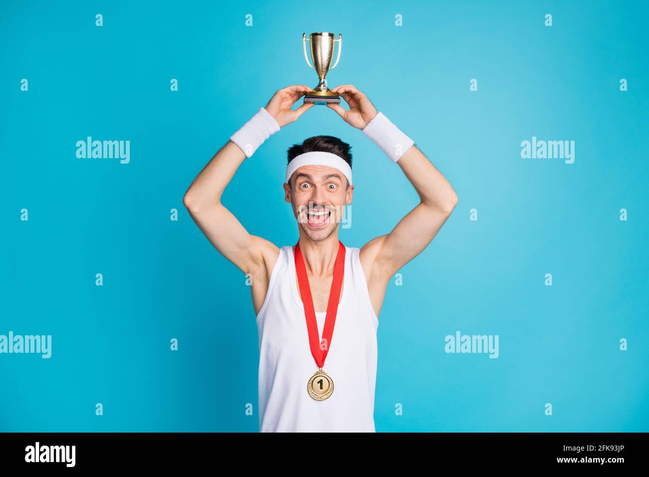 Photo of shocked brunette happy man wear headband golden medal lift ...