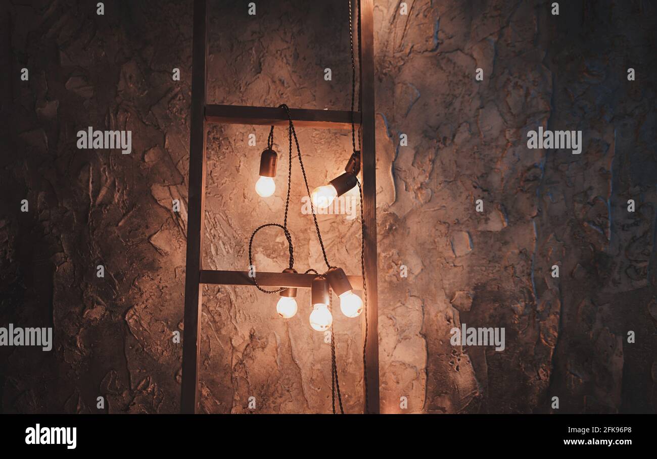 many bright light bulbs hang on a ladder in the loft interior Stock ...